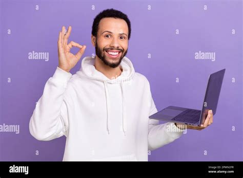 Photo Of Cheerful Handsome Guy Hold Netbook Arm Fingers Show Okey