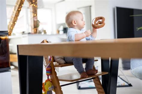 Premium Photo Happy Infant Sitting At Dining Table And Playing With