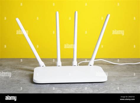 New White Wi Fi Router On Grey Textured Table Against Yellow Background Stock Photo Alamy