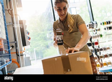 Female Worker Sealing Or Taping Packing Case With Adhesive Tape Using Dispenser At Warehouse