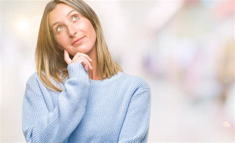 손으로 턱 질문 잠겨있는 표현에 대 한 생각에 고립 된 배경 위에 겨울 스웨터를 입고 젊은 아름 다운 여자 사려깊은 얼굴 미소 의심 개념입니다 가을에 대한 스톡 사진 및