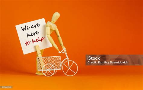 흰 종이가 있는 나무 옷핀 텍스트 우리는 도움을 여기 있다 미니어처 자전거 모델과 인간의 나무 모델 아름다운 오렌지 배경 비즈니스 및 지원 개념 복사 공간 0명에 대한 스톡