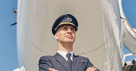 비행기 동체 아래에 팔짱을 낀 사려 깊은 젊은 비행사의 낮은 각도 사진 Unsplash의 팔 이미지