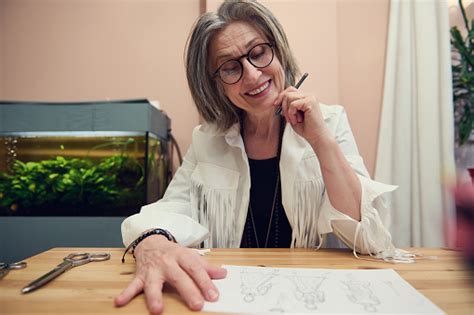 스타일리시한 우아한 여성 패션 디자이너 드레스메이커 재단사 연필과 드로잉 스케치를 들고 의류를 위한 스케치를 들고 새로운 드레스 컬렉션을 개발 60 69세에 대한 스톡 사진