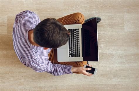 Premium Photo Top View Of Man Sitting On The Floor And Working With A Laptop And Smartphone In