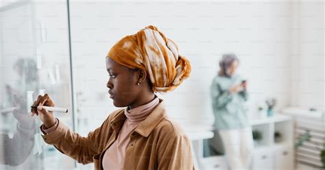 현대 아프리카계 미국인 여성의 측면 초상화는 사무실에서 일하는 동안 유리 벽에 메모를 쓰고 공간을 복사한다 사진 Unsplash의 아프리카 민족 이미지