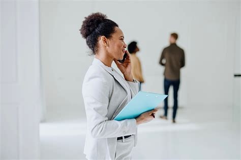 새로운 집을 구입에 관심이 부부 근처에 서있는 동안 클립 보드 미소와 응답 전화와 부동산 에이전트 부동산 중개업자에 대한 스톡 사진 및 기타 이미지 Istock