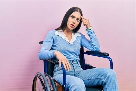 Beautiful Woman With Blue Eyes Sitting On Wheelchair Pointing Unhappy To Pimple On Forehead