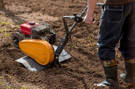 기치 한 남자 농부가 경작자와 함께 땅을 쟁기질합니다 정원에서 경작을위한 농업 기계는 수확기를 결합합니다 가루로 빻은에 대한 스톡 사진 및 기타 이미지 Istock