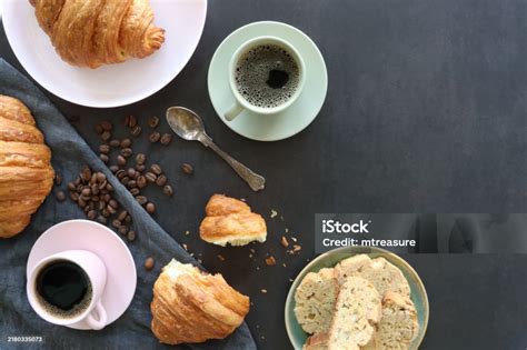 회색 모슬린에 분홍색과 녹색의 컵과 블랙 커피 접시 갓 구운 아침 식사 패스트리 부스러기 및 엎질러진 볶은 커피 콩 전체 및 찢어진 모든 버터 크로와상 접시에 크로와상과