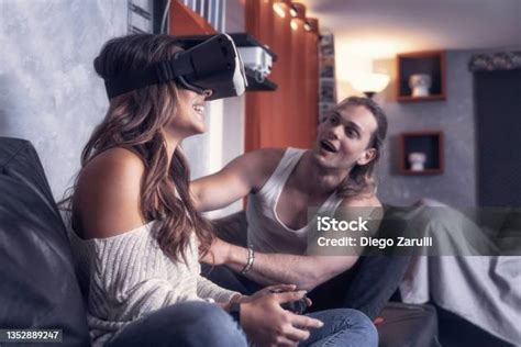 백인 남자의 쾌활한 현대 부부는 스튜디오 하우스의 거실에서 함께 재생합니다 남자 남자 즐길 수 있는 A 소녀 놀이 비디오 게임 와 휴대 전화 고글 들고 조이패드 데 재미