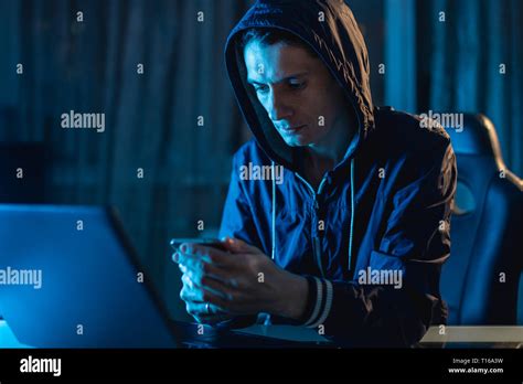 Cybercriminal Hacker In The Hood Typing Program Code While Stealing Access Databases With