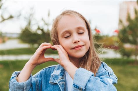 Premium Photo A Little Blonde Girl Shows A Heart Sign Made With Her