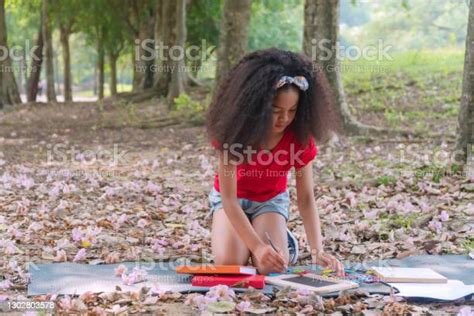 혼합 인종 아이 소녀 곱슬 머리와 공공 공원의 매트에 앉아 책 작은 귀여운 소녀 긍정적 인 나무 느낌에서 재생 휴식과 자연 배경에 뭔가를 배울 수 있습니다 6 7 살에 대한