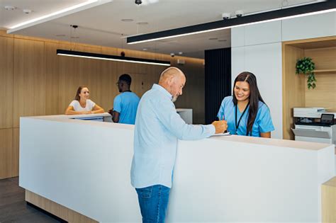 노인은 접수 데스크에 서서 의료 양식을 작성하는 방법을 설명하는 쾌활한 간호사의 말을 주의 깊게 듣습니다 남자에 대한 스톡 사진 및 기타 이미지 Istock