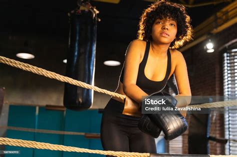 여자 파이터 걸 파워 권투 글러브를 끼고 권투 링에 서서 밧줄에 기대어 기다리고 쉬고 있는 아프리카계 미국인 여성 파이터 강한 강력한 소녀 근력 운동 운동에 적합합니다 18