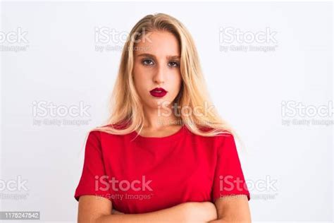고립 된 흰색 배경 회의론자 와 긴장 위에 서 빨간색 캐주얼 티셔츠를 입고 젊은 아름다운 여성은 교차 팔로 얼굴에 표정을 거부 부정적인 사람 T 셔츠에 대한 스톡 사진 및