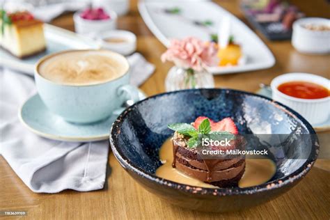 딸기와 민트 잎으로 장식 된 캐러멜 초콜릿 스폰지 케이크 카페에서 아침 식사 모닝 커피 카푸치노와 테이블에 디저트를 많이 0명에 대한 스톡 사진 및 기타 이미지 Istock