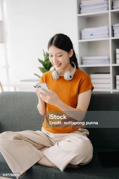 집에서 쉬고 있는 웃는 소녀는 스마트폰 태블릿 노트북 흰색 헤드폰을 착용하고 음악을 재생하고 있다 소파에 20 24세에 대한 스톡 사진 및 기타 이미지 Istock