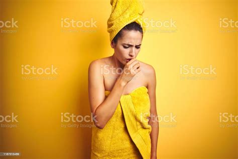 몸에 샤워 타월을 입고 아름다운 여성은 추위 또는 기관지염의 증상으로 기분이 좋지 기침 노란색 고립 된 배경을 통해 머리 헬스케어 개념 기침하기에 대한 스톡 사진 및 기타