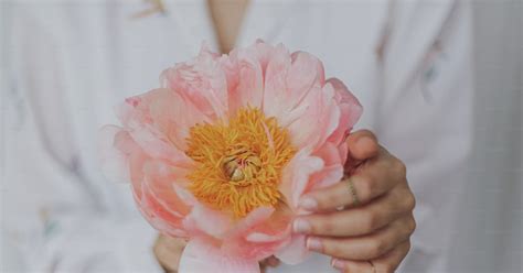 손에 분홍색 모란을 가진 관능적 인 아름 다운 여자입니다 보헤미안 꽃 셔츠를 입은 젊은 세련된 여성이 큰 모란 꽃을 부드럽게 들고 있다 부드러운 부드러운 이미지 봄의