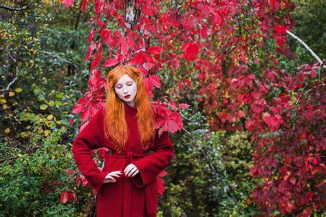 밝은을 바탕에 빨간 코트에 붉은 스트레이트 머리를 가진 여자 창백한 피부와 파란 눈과 손가락 및 빨간 손톱에 반지와 함께 밝은