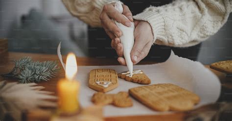 크리스마스 진저 브레드 쿠키를 촛불과 장식품으로 나무 테이블에 장식합니다 프로스팅으로 진저 브레드 하우스 만들기를 닫습니다 분위기 있는 분위기 있는 이미지 휴일 준비