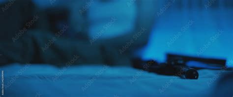 Close Up Of M16 Rifle Lying On A Bed With Ptsd Soldier Siiting On Bed