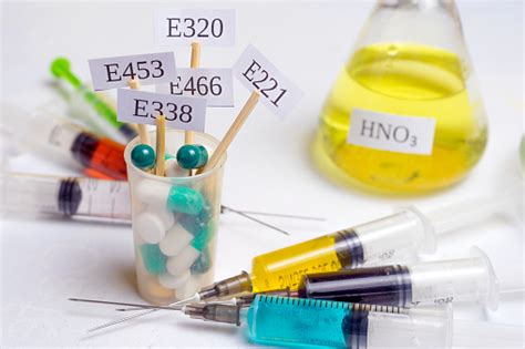 유해한 식품 첨가물 여러 가지 색깔의 알 약 유리에 코드 전자 보충 접시 인근에는 질산염 화학 물질 및 첨가제를 곁들인 주사기가 있습니다 메인 질산 테이블에 질산이있는
