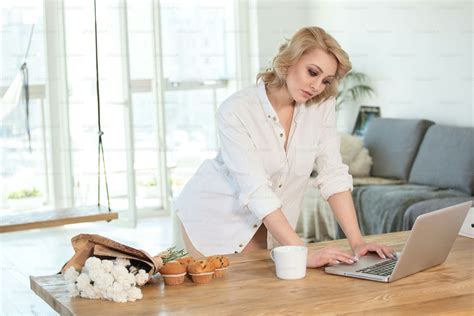 재택 근무 프로세스 개념입니다 금발의 백인 젊은 여성은 아침에 컴퓨터에서 일합니다 책상 위에 컵케이크와 신선한 꽃이 놓여 있다 사진 Unsplash의 청년 성인 이미지