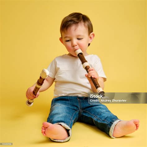 유아 아기는 플루트 스튜디오 노란색 배경에 관악기를 가진 아이를 연주합니다 블록 플루트를 연주하는 행복한 어린이 음악가 1 세 4 개월 된 아이 리코더에 대한 스톡 사진 및
