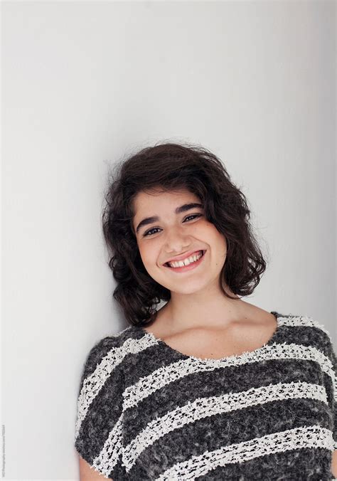 Portrait Of Young Smiling Woman Leaning On A Wall By Stocksy