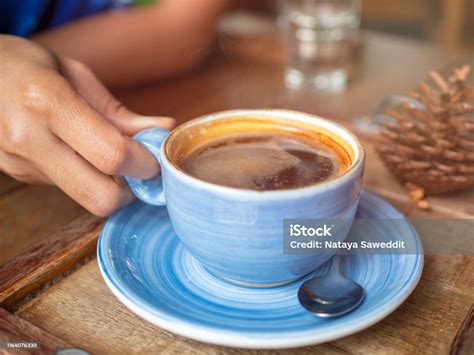 뜨거운 미국 커피는 연기와 햇빛이 있는 카페의 나무 바닥 테이블에 놓인 파란색 세라믹 솔루션입니다 아침 선택적 초점에서 커피