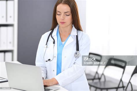 직장에서 의사 여자입니다 클리닉 또는 응급 병원 리셉션 데스크 근처에 서 있는 동안 랩톱 컴퓨터를 사용 하는 여성 의사의 초상화 의학 및 건강 관리 개념 가리키기에 대한