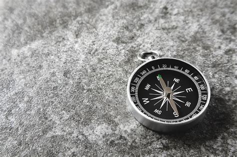 Premium Photo Magnetic Compass Laying On Stone Surface And Pointing