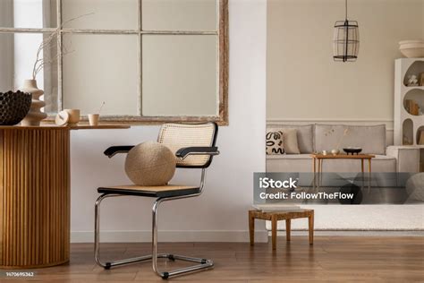 따뜻하고 아늑한 식사 공간과 둥근 커피 테이블 등나무 의자 베개 나무 바닥 창문 베이지색 소파 세련된 안락의자 개인 액세서리가