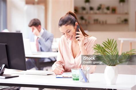 사무실 책상에 앉아 서류를 하는 동안 그녀의 휴대 전화에 누군가와 이야기 하는 행복 한 사업가의 초상화 샷 30 39세에 대한 스톡 사진 및 기타 이미지 Istock