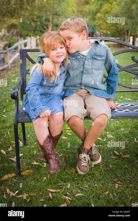 Happy Young Brother And Sister Sitting Together On A Bench Outside