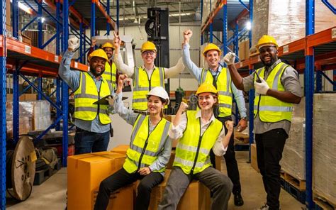 Group Of Happy Warehouse Workers Celebrating Success In Warehouse Stock