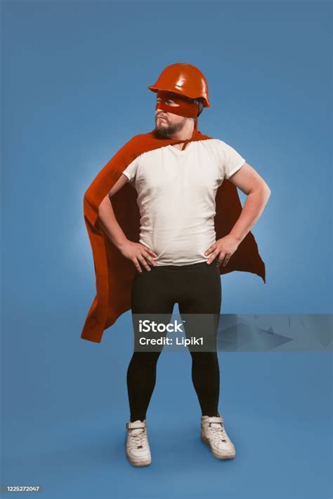 슈퍼 영웅 엔지니어 빨간 헬멧 마스크 케이프를 입고 엉덩이에 손을 얹은 남자 페이드 데님 블루 배경에 격리 개념에 대한 스톡