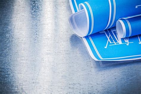 Premium Photo Blue Rolled Up Blueprints On Scratched Metallic Background Construction Concept