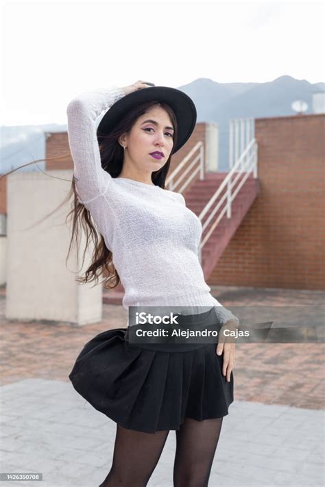긴 머리가 바람에 움직이는 여성 모델 패션 액세서리로 모자를 착용 스웨터와 스커트 라틴 여성 개념에 대한 스톡 사진 및 기타