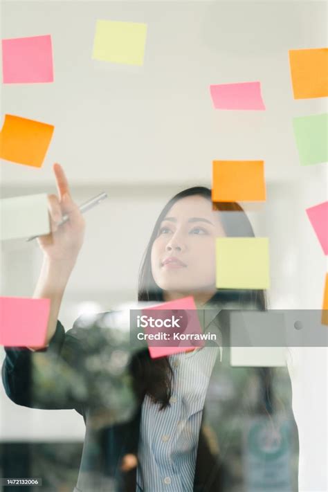 브레인 스토밍의 개념은 사업가가 유리 벽에 놓는 포스트잇 메모를 사용하여 아이디어를 공유 할 때 예시됩니다 30 34세에 대한