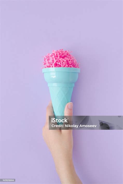 여자 손은 파스텔 보라색 배경에 아이스크림 플라스틱 콘과 핑크 종이 아이스크림 스쿱을 잡고 있습니다 최소한의 여름 개념 음식에 있는 마이크로 플라스틱 재활용 건강한 생활