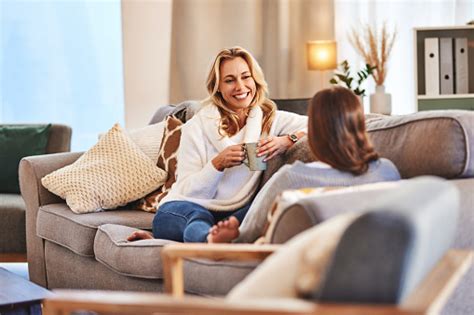 커피 미소 행복한 여자는 소파에 앉아 대화를 나누고 휴식을 취하고 양질의 시간을 보내는 아파트를 만든다 거실 소파에 앉은 엄마와 딸 함께 이야기하고 웃고 유대감과 행복 12