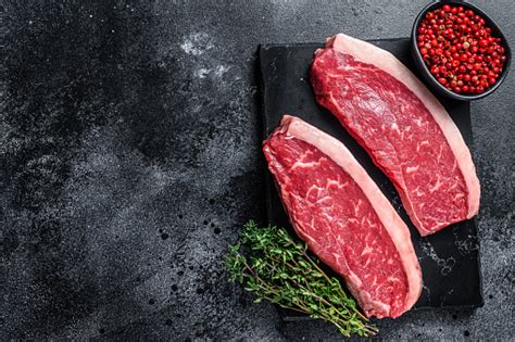 대리석 보드에 생 캡 럼프 스테이크 또는 상단 등심 쇠고기 고기 스테이크 검은 색 배경 맨 위 보기입니다 복사 공간 날것에 대한
