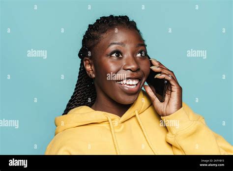 Young Black Woman Wearing Hoodie Talking On Mobile Phone Isolated Over