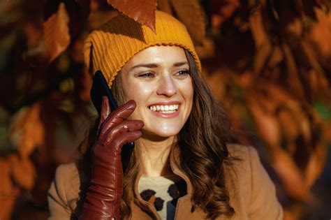 베이지색 코트와 오렌지 모자를 쓰고 전화통화를 하는 행복한 여자 10월에 대한 스톡 사진 및 기타 이미지 10월 11월 40 44세 Istock