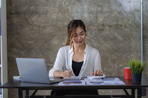 문서와 노트북으로 사무실에서 결과를 보여주는 차트와 그래프를 작업하는 아시아 사업가 재무 지표를 계산하는 작업자 문서 미소 짓고