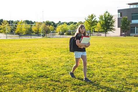 배낭을 착용하고 바인더를 들고 고등학교 옆에 있는 축구장을 걷는 행복한 학생 가방에 대한 스톡 사진 및 기타 이미지 가방 건물 외관 걷기 Istock